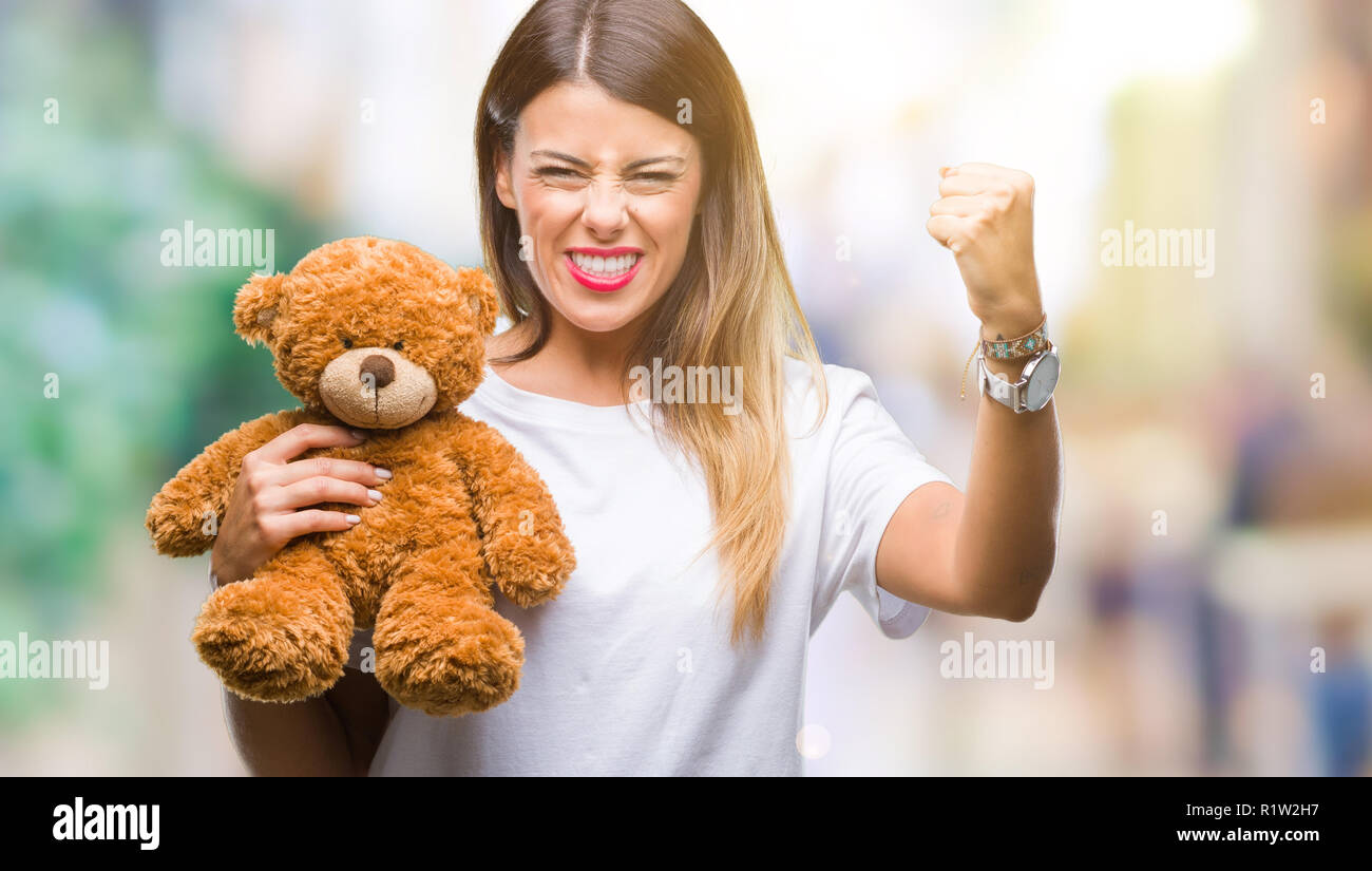 Young beautiful woman holding teddy bear plush over isolated background ...