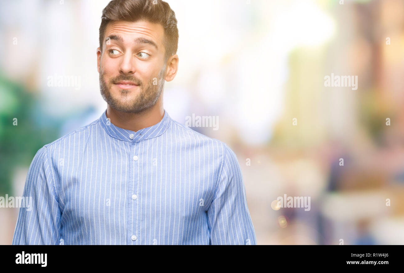 Young handsome man over isolated background smiling looking side and ...