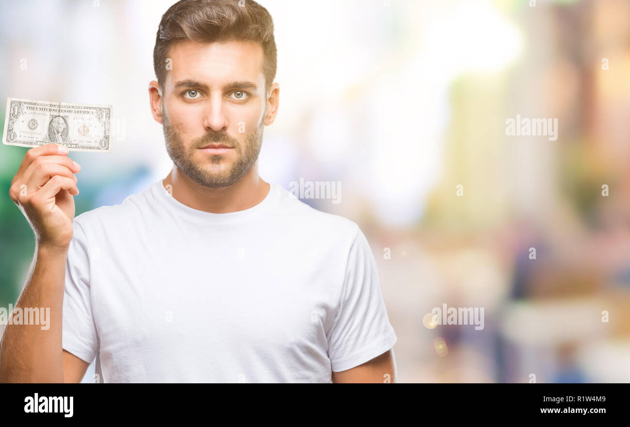 Young handsome man holding dollars over isolated background with a ...