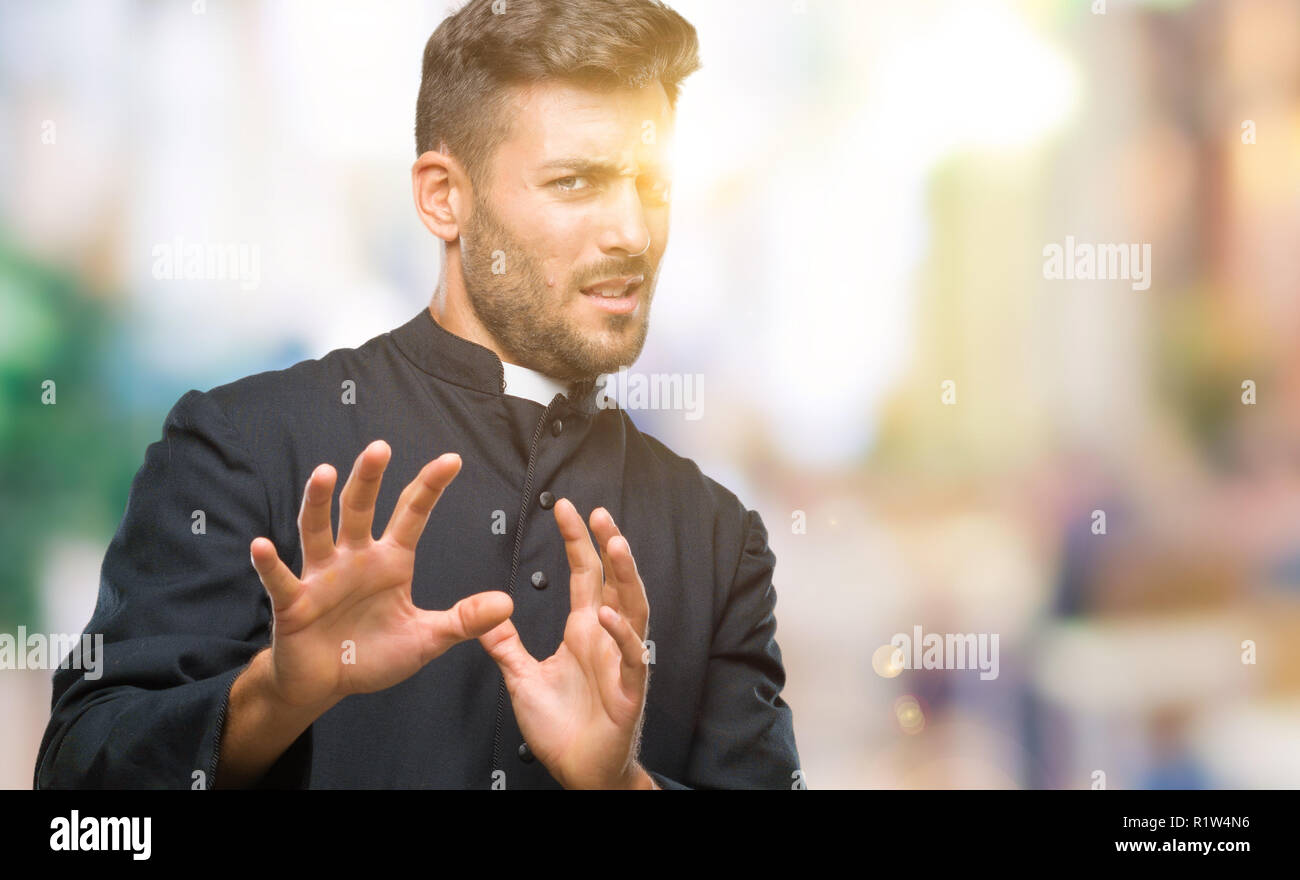 Young catholic christian priest man over isolated background disgusted ...