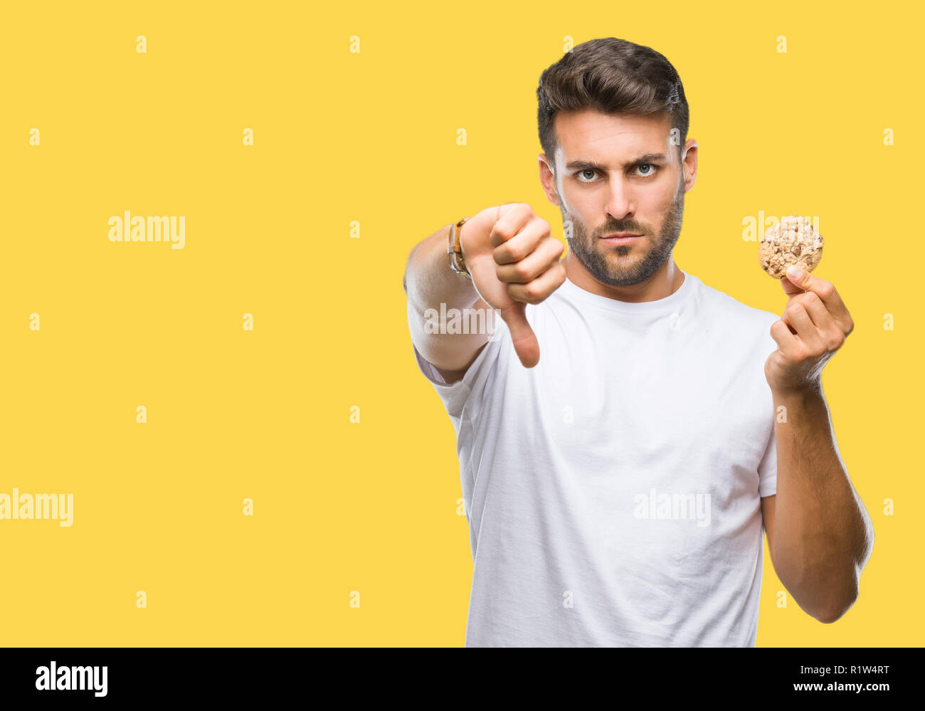Young handsome man eating chocolate chips cookie over isolated ...