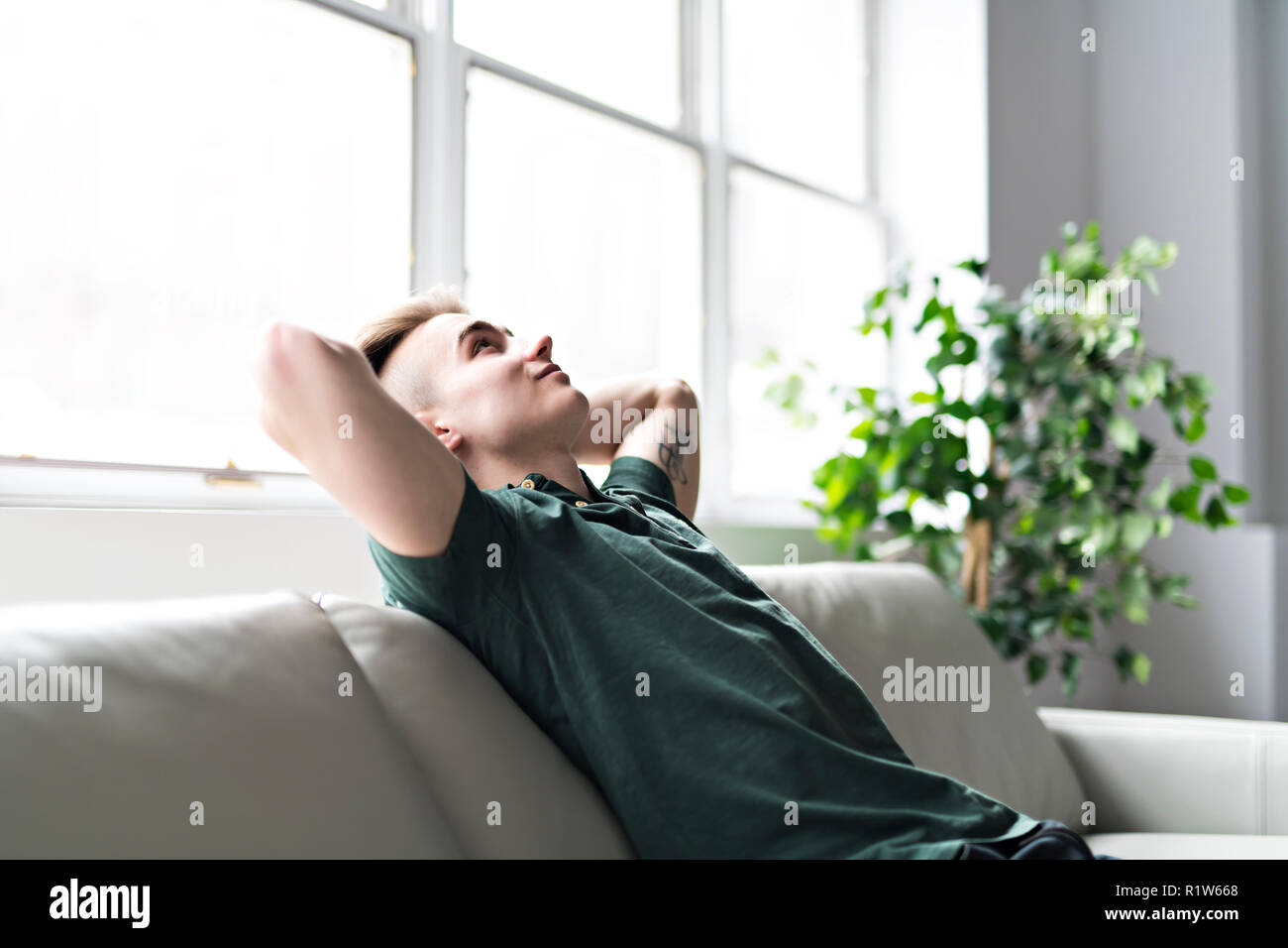 A Young man sitting on coach rest at home Stock Photo - Alamy