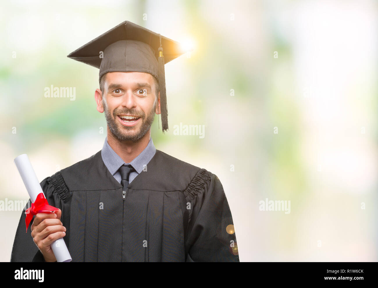 Young handsome graduated man holding degree over isolated background ...
