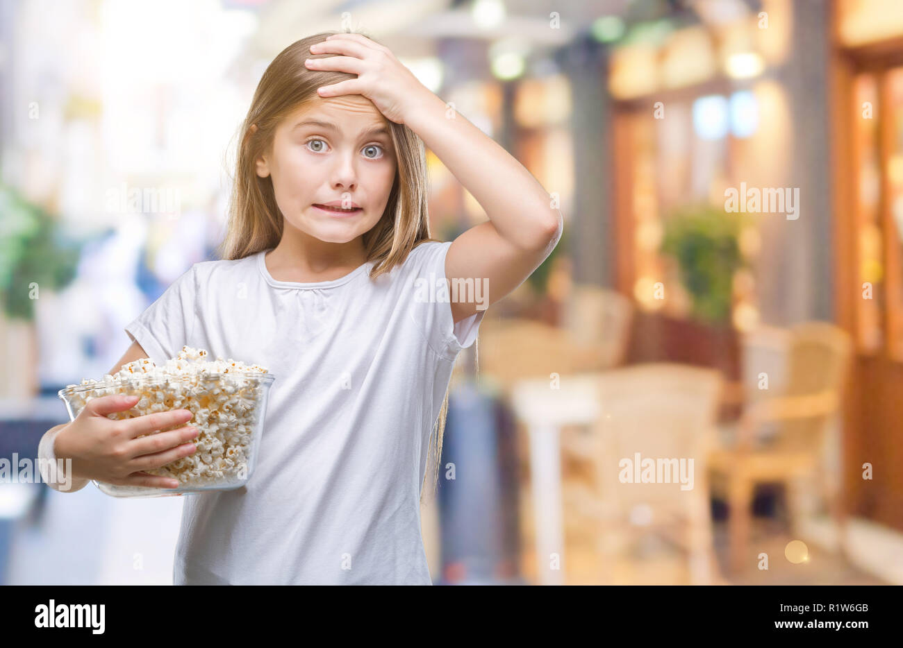 Young beautiful girl eating popcorn snack isolated background stressed ...
