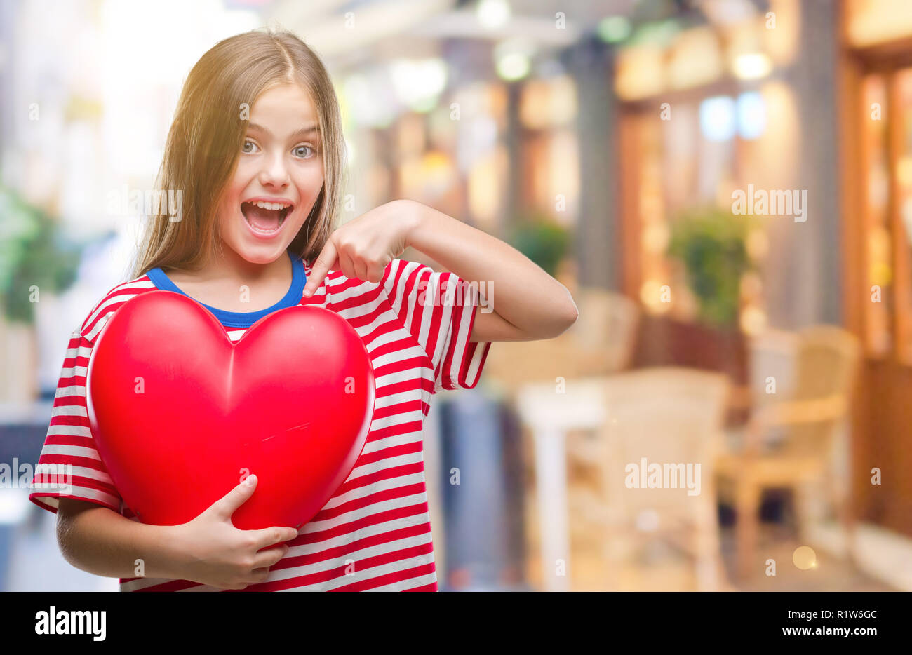 Young beautiful girl holding red heart over isolated background with ...
