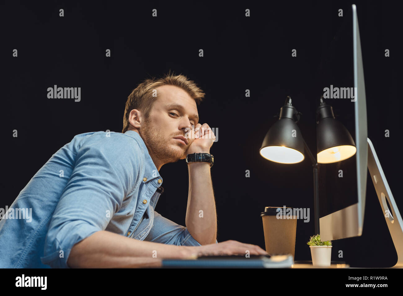 low angle view of overworked young businessman sitting at table with ...