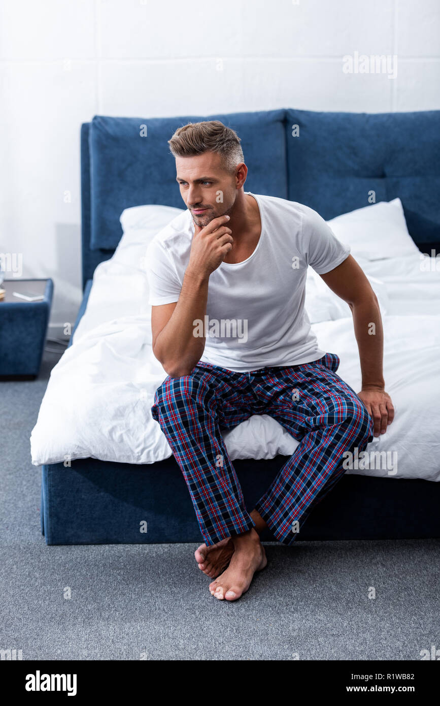 thoughtful adult man sitting on bed during morning time at home Stock ...