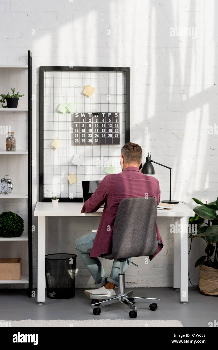 back view of man sitting at workplace at home office Stock Photo - Alamy