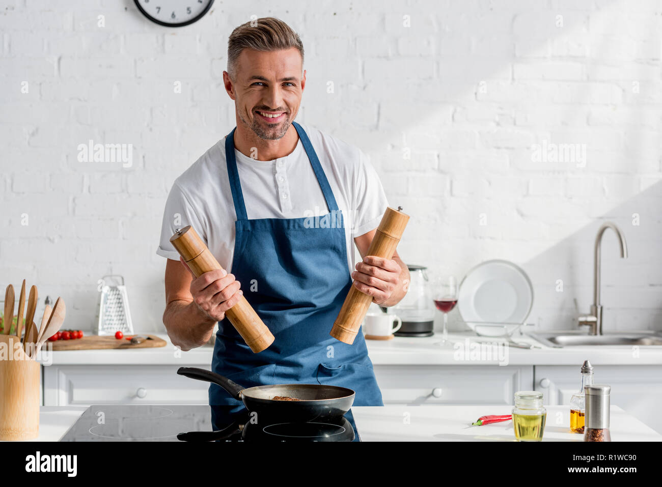 adult handsome man holding salt and pepper mills at kitchen Stock Photo ...