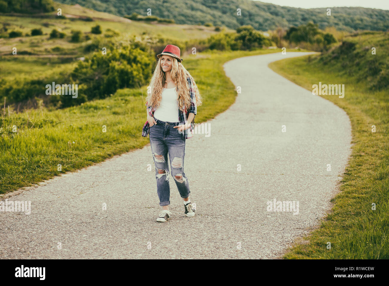 Beautiful young woman enjoys walking at the country road Stock Photo ...