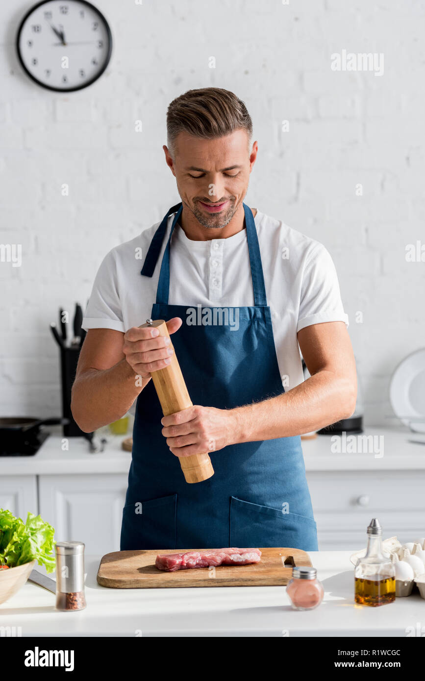 Handsome smiling man seasoning steak before cooking Stock Photo - Alamy