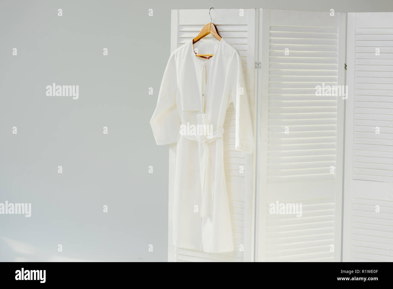 elegant white dress hanging on wooden room divider Stock Photo - Alamy