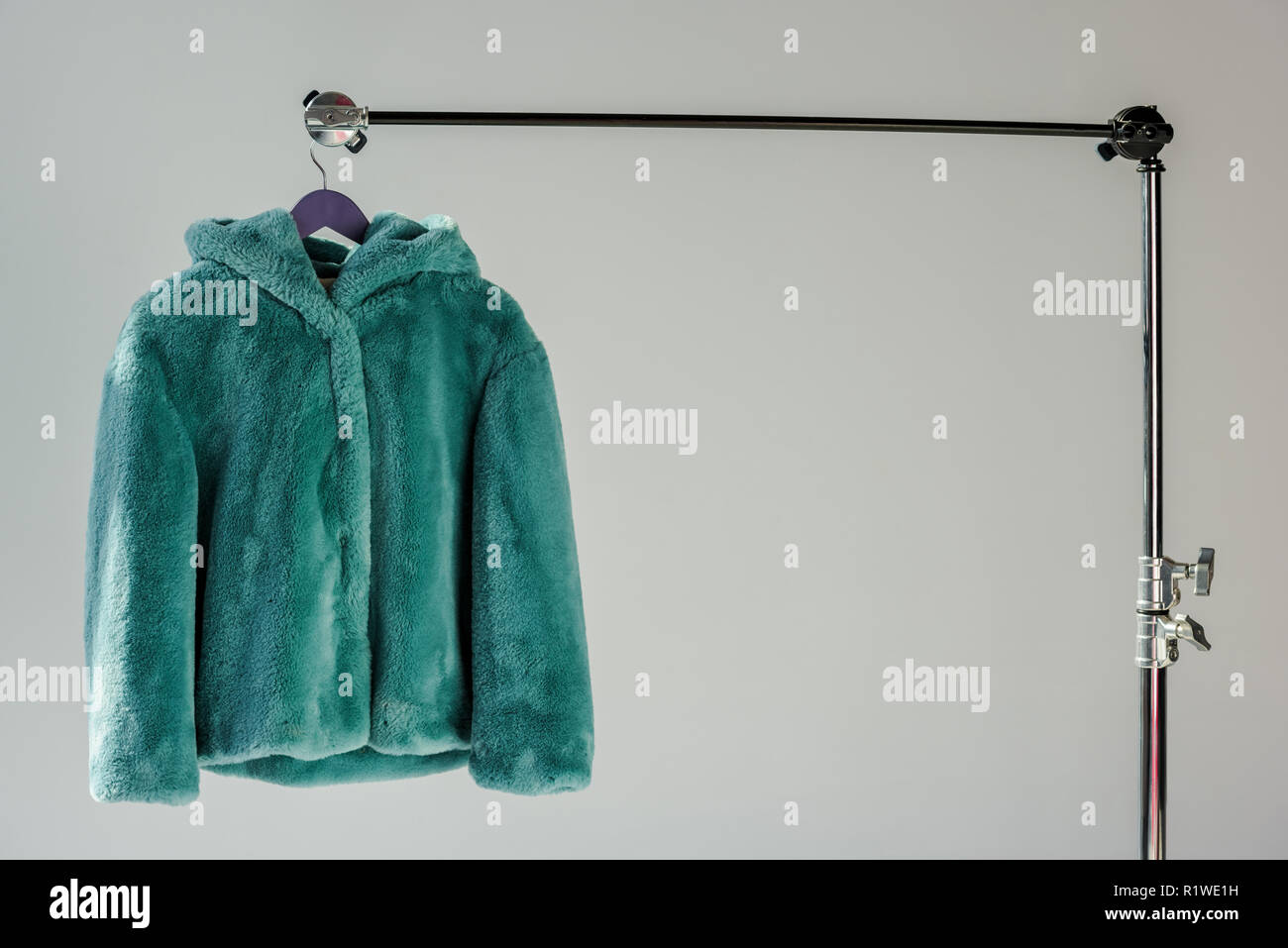 fluffy green faux fur coat hanging on rack at grey background with ...