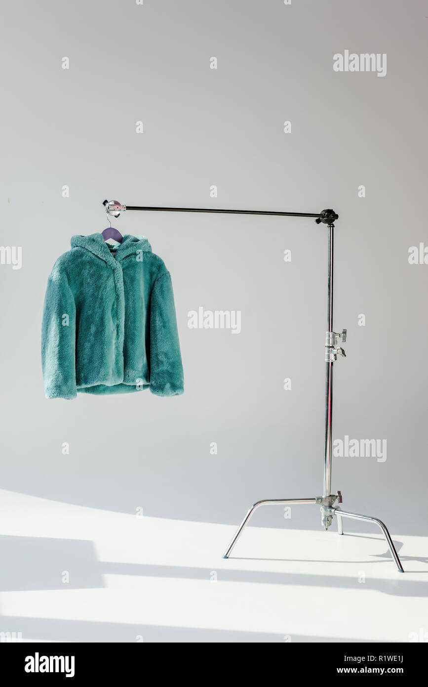 fluffy green faux fur coat hanging on rack at grey background Stock ...