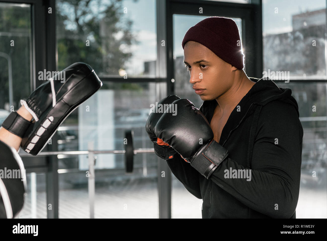 serious african american boxer in boxing gloves practicing with trainer ...