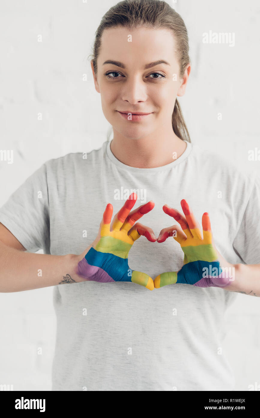 smiling young transgender man making heart sign with hands in colors of ...