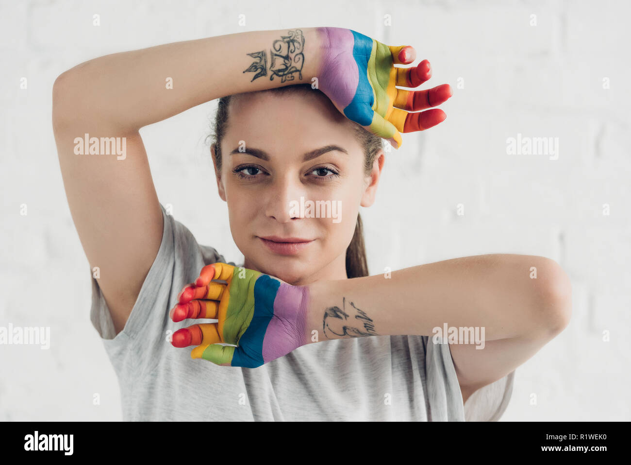 young transgender man with hands painted in colors of pride flag in ...