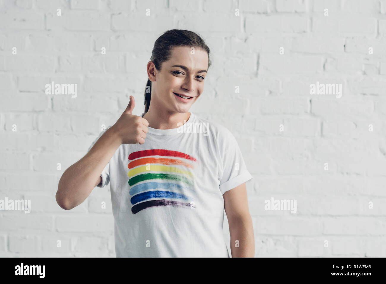 happy transgender man in white t-shirt with pride flag showing thumb up ...