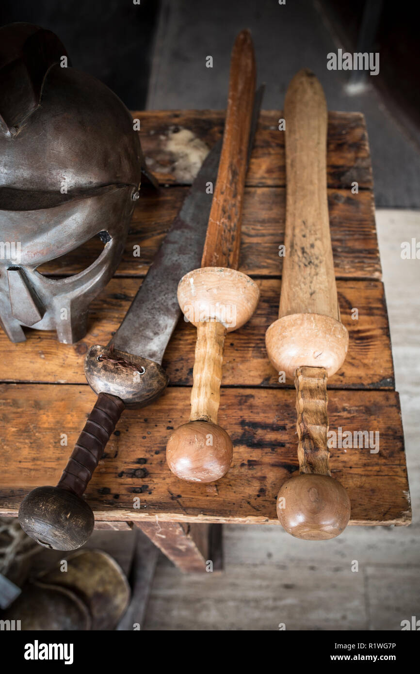 Gladiators table with helmet and wooden training swords. Ancient roman ...