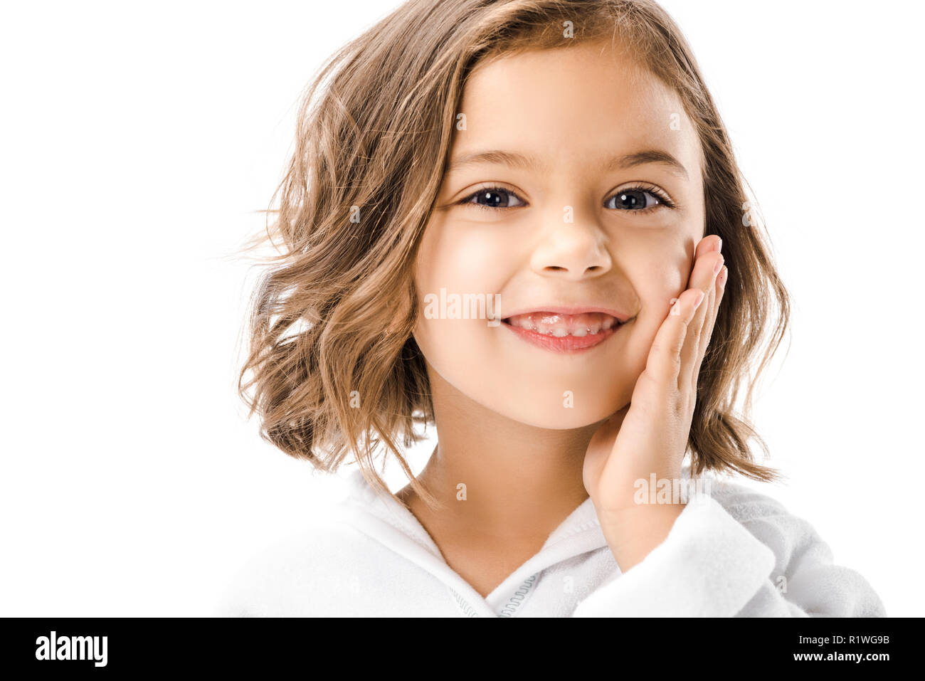 little smiling kid touching face and looking at camera isolated on ...
