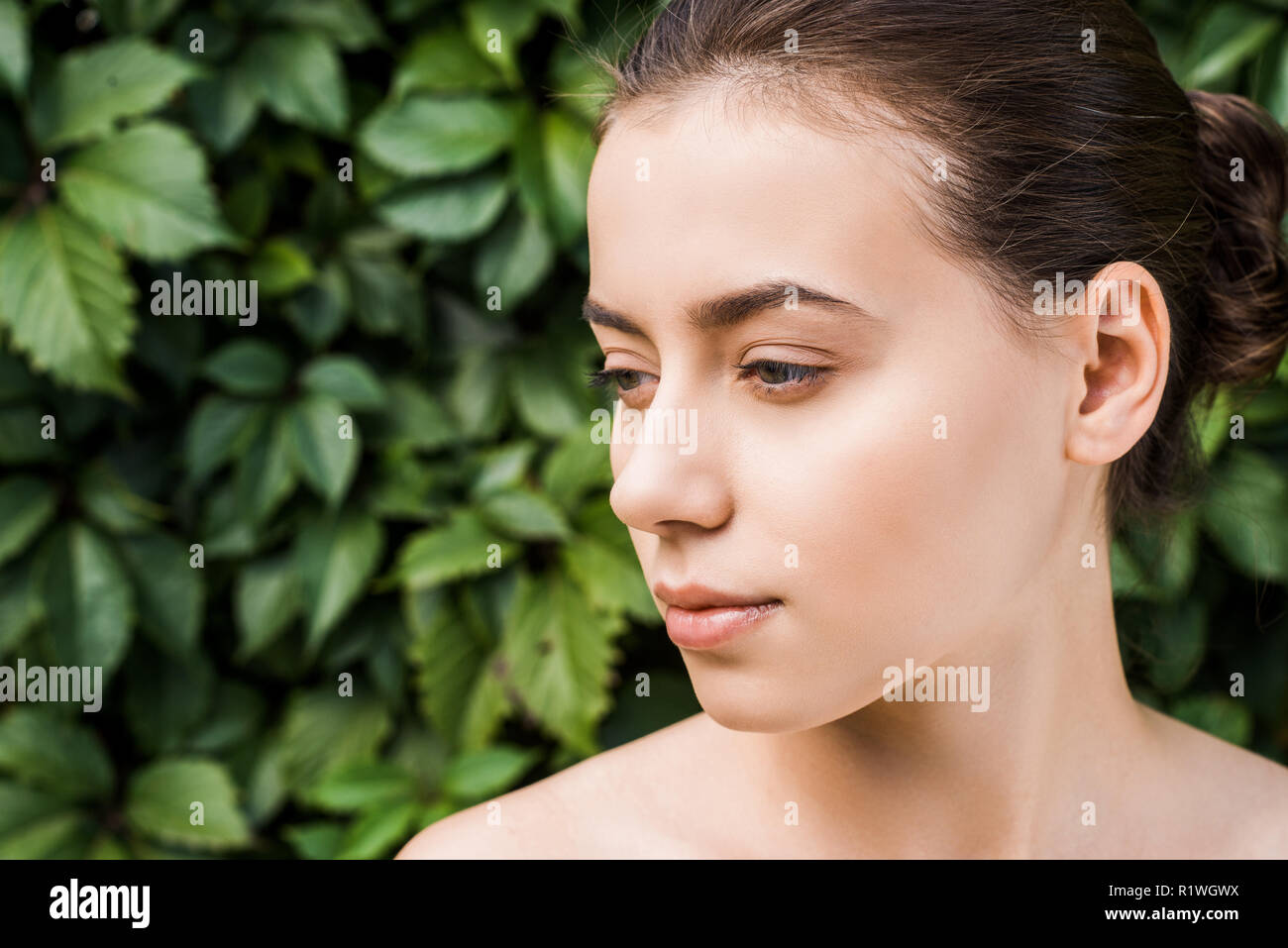 thoughtful young woman with green leaves at background Stock Photo - Alamy