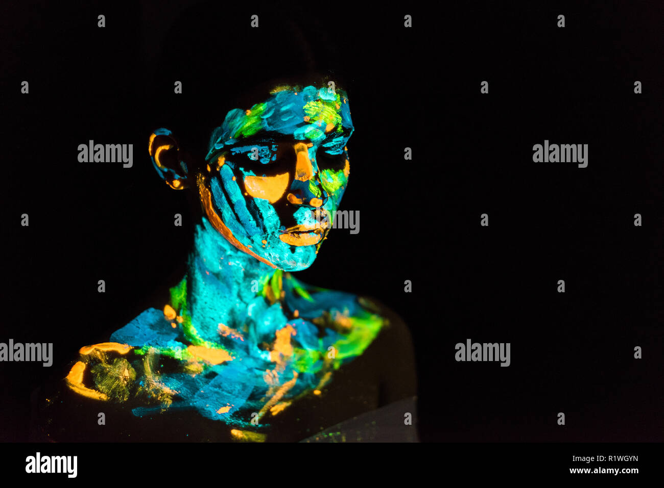 model with colorful neon paints on body posing on black backdrop Stock ...