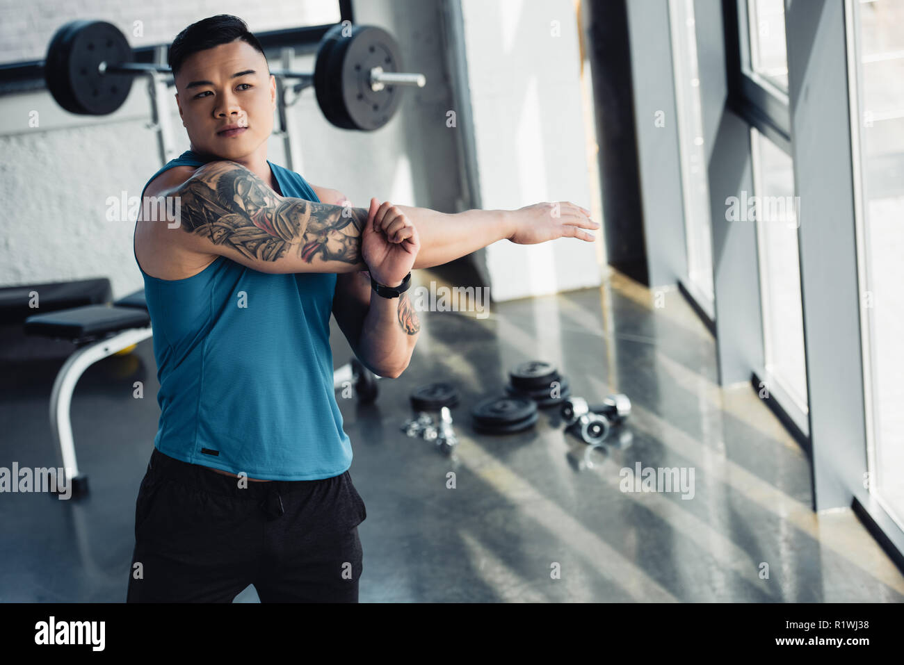 Asian sport young man doing warming-up exercises, full length portrait ...
