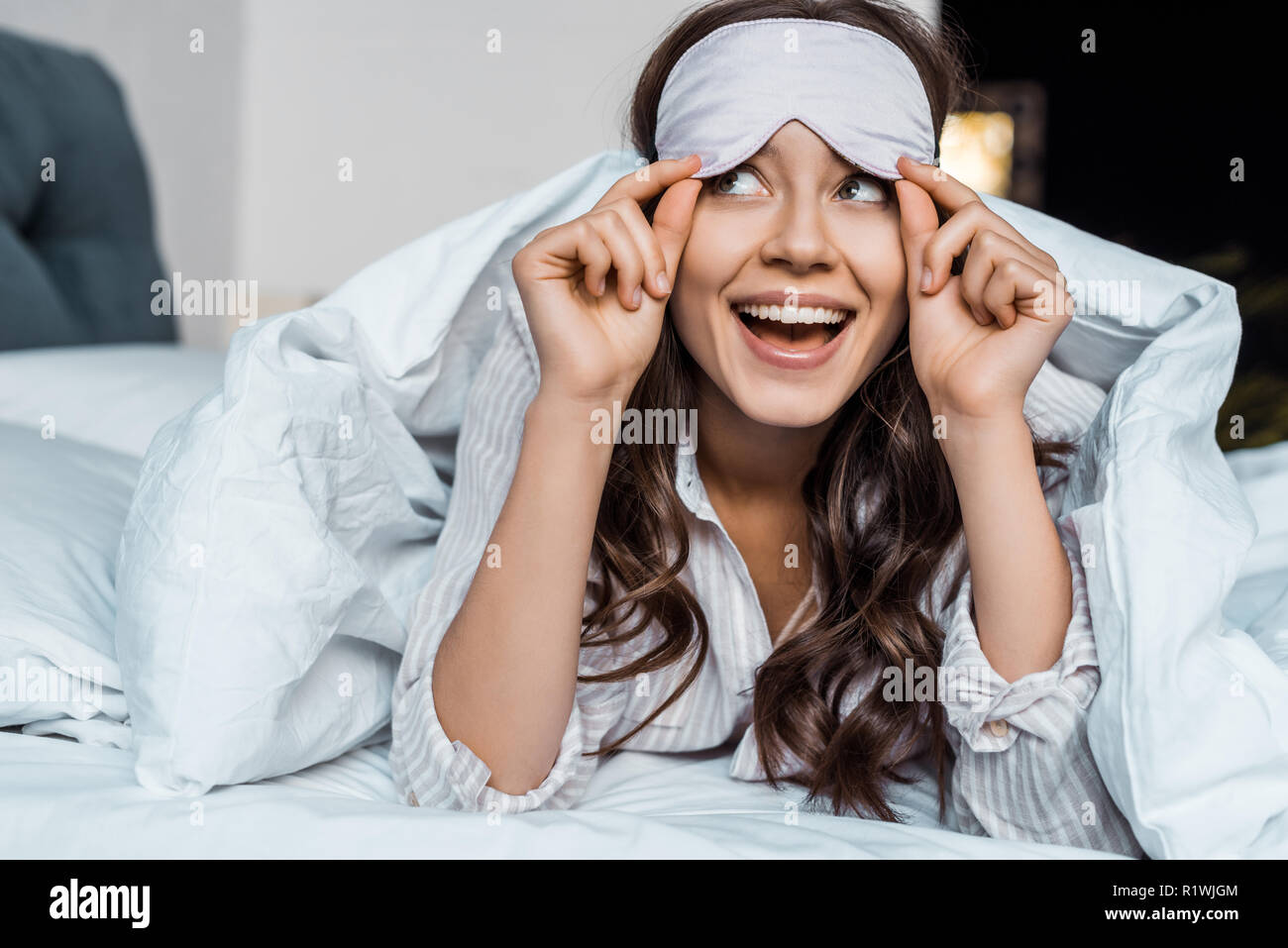 beautiful excited girl in sleeping eye mask lying in bed Stock Photo ...
