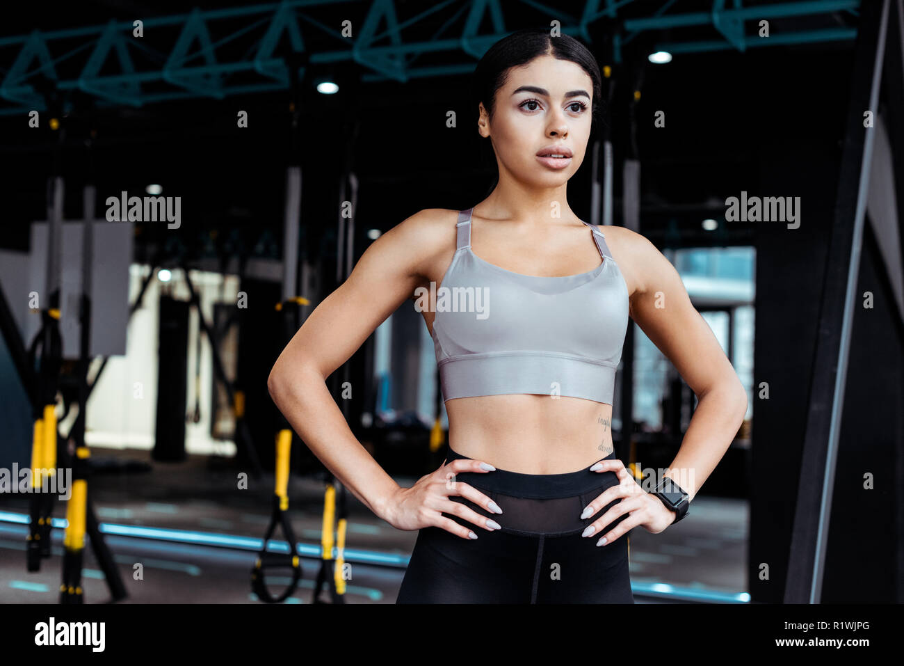 Attractive strong girl standing akimbo in fitness gym Stock Photo - Alamy