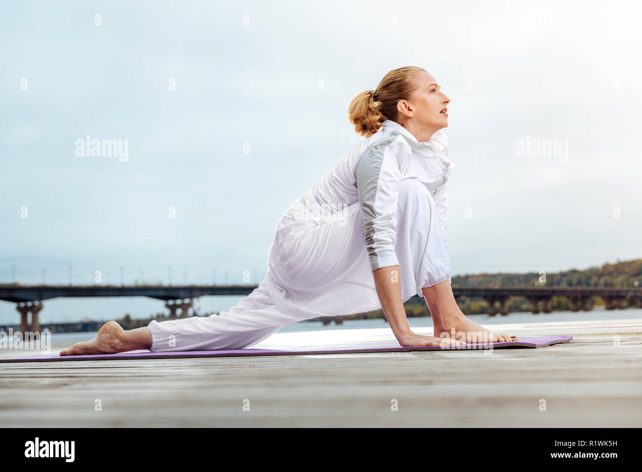 Young woman performing stretching exercises near the river Stock Photo ...