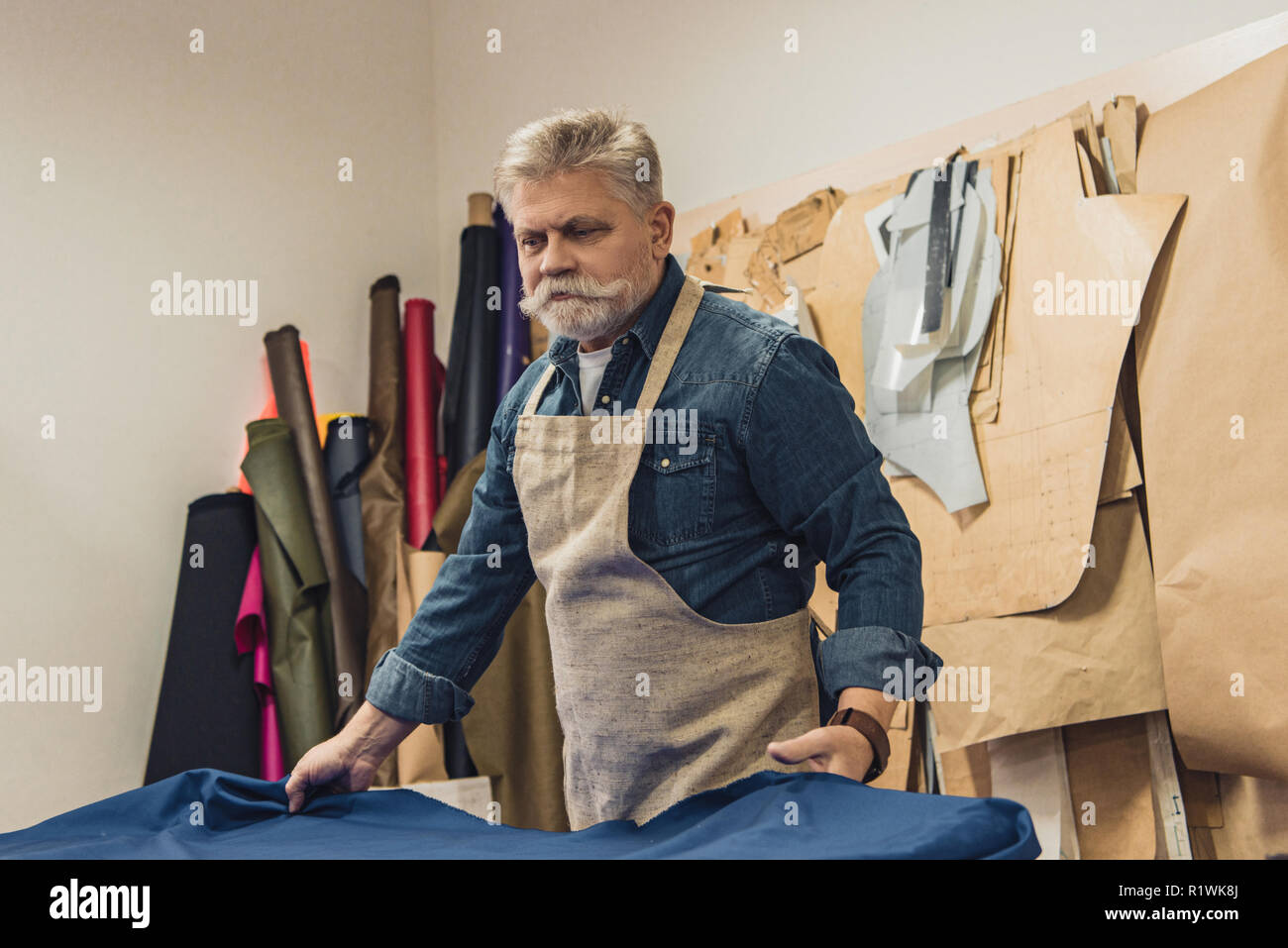 confident male handbag craftsman putting fabric on working table at ...