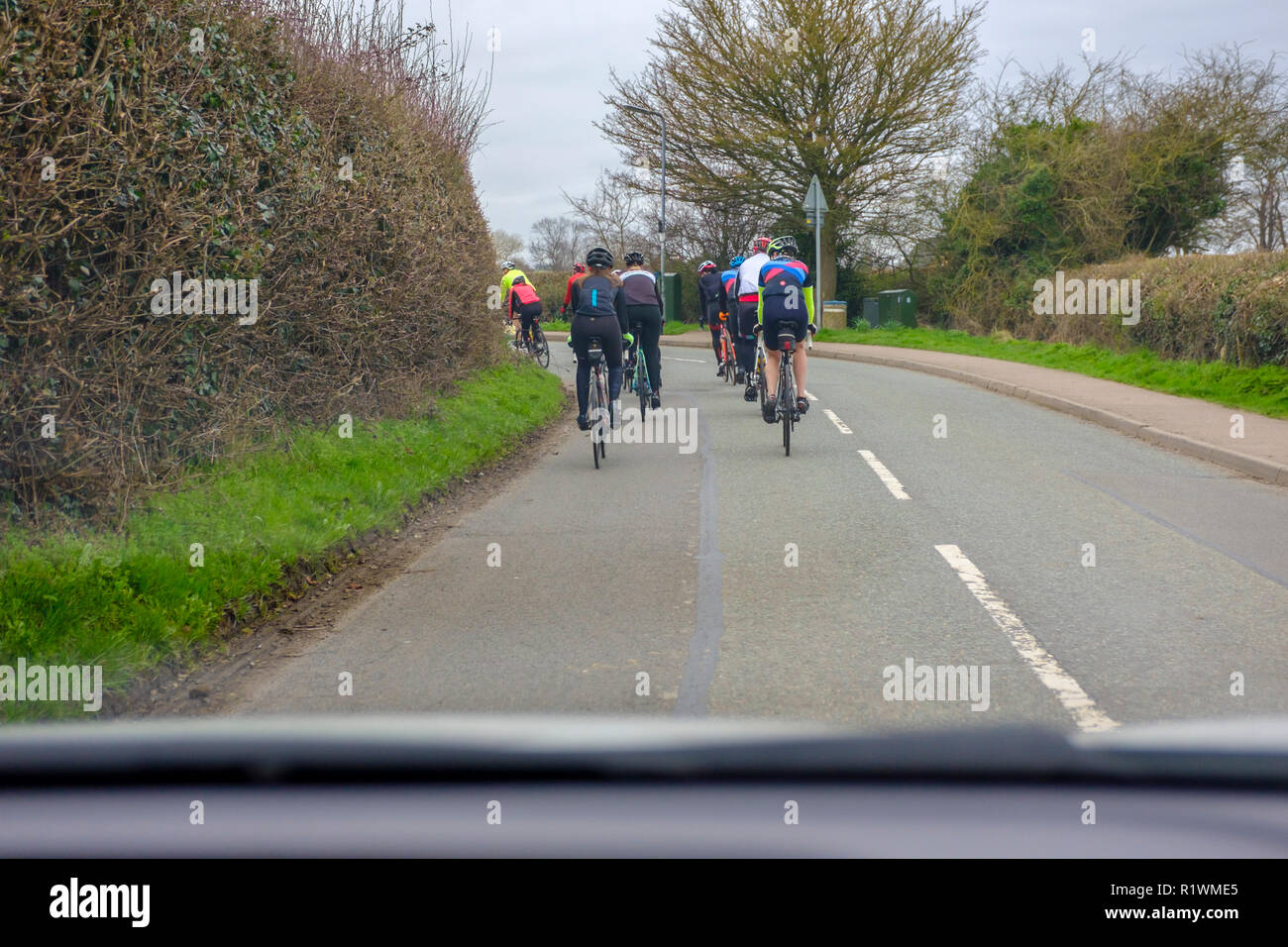 View through car windscreen of a Group of ten road cyclists, cycling ...