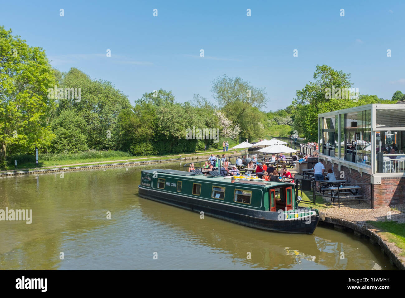 Narrowboat moored alongside a canal side pub and restaurant, on the ...