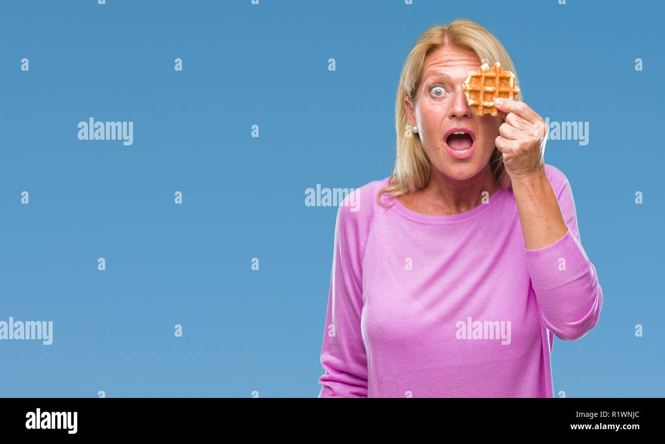 Middle age blonde woman eating sweet waffle over isolated background ...