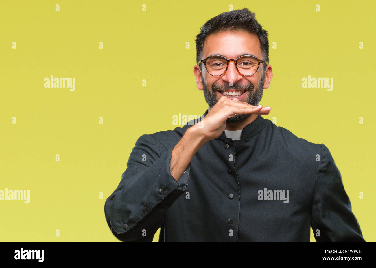 Adult hispanic catholic priest man over isolated background gesturing ...