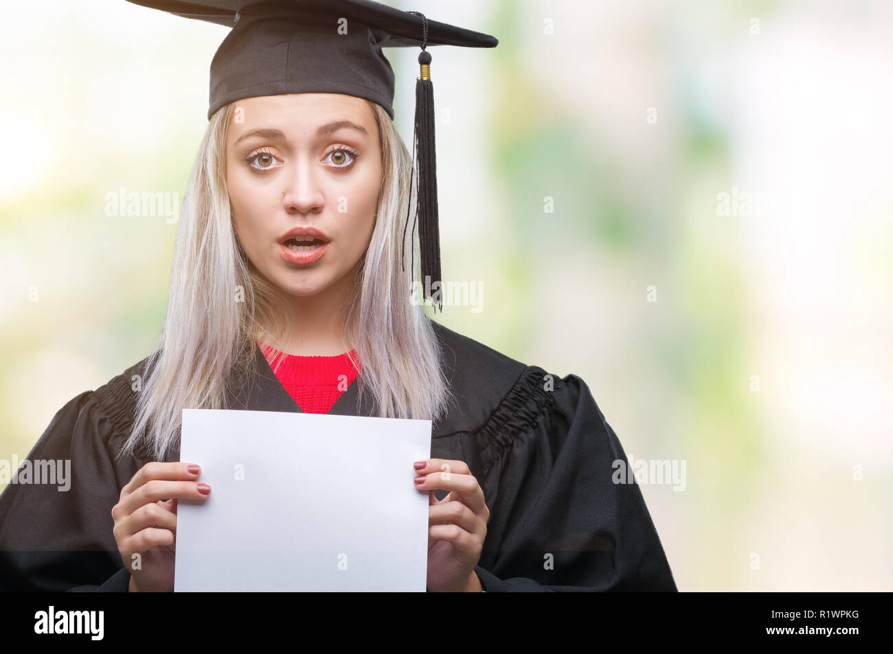 Young blonde woman wearing graduate uniform holding degree over ...