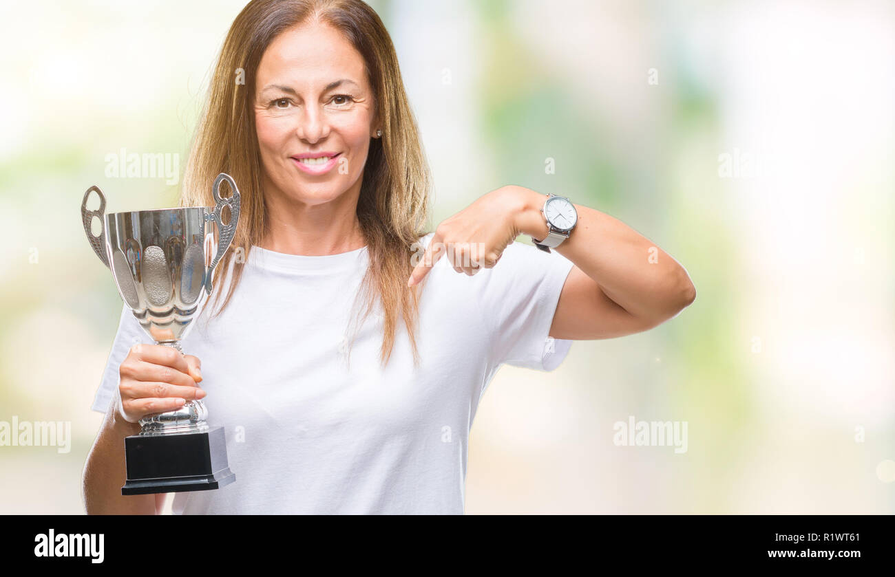 Middle age hispanic winner woman celebrating award holding trophy over ...