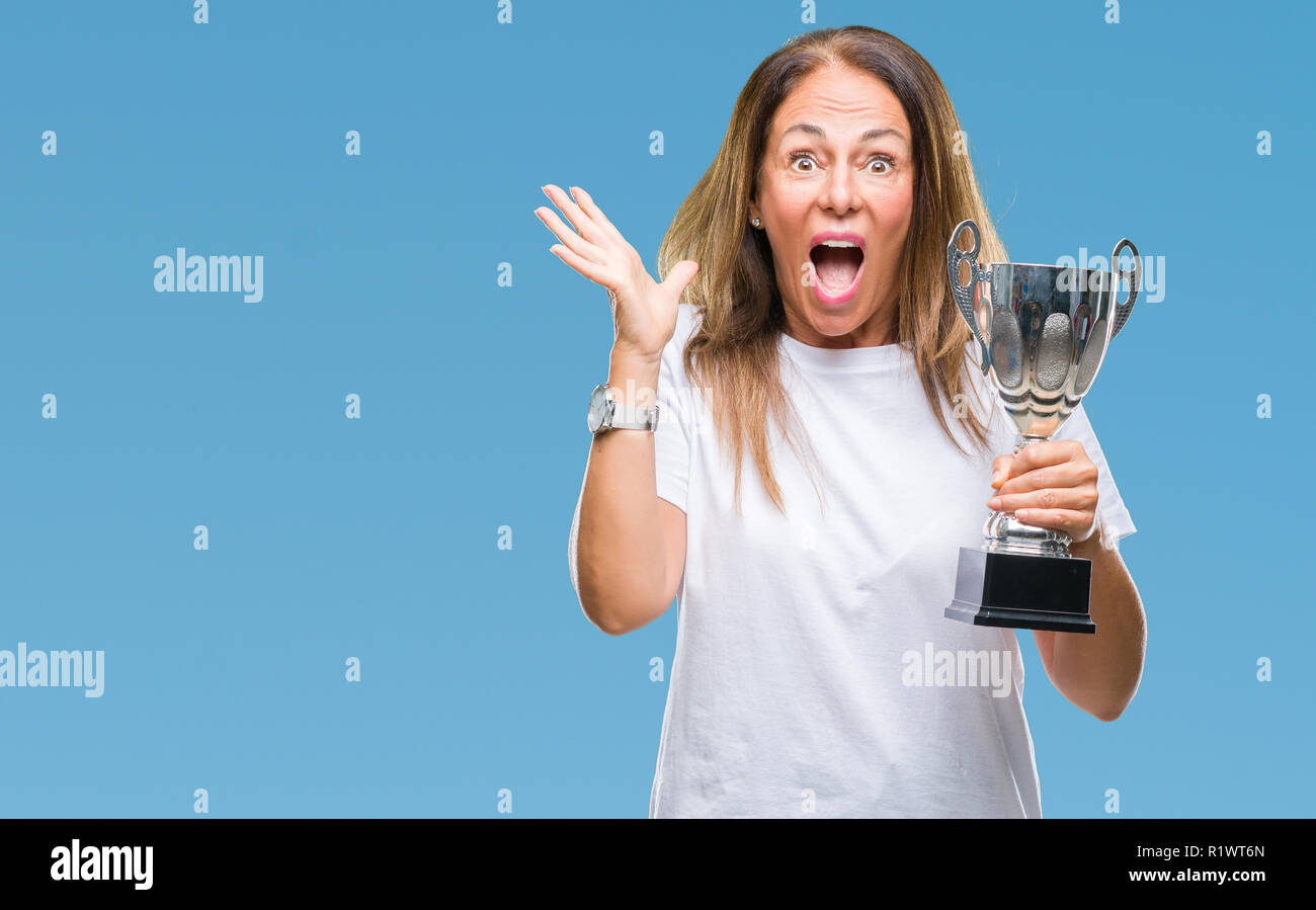 Middle age hispanic winner woman celebrating award holding trophy over ...
