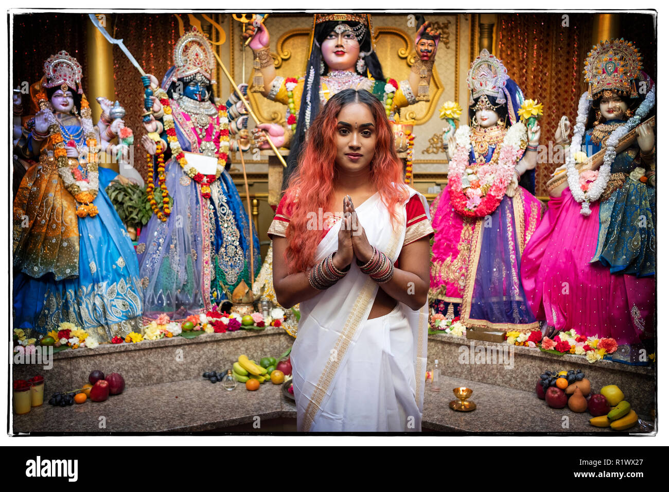 Portrait of a beautiful Hindu young woman in front of statues of ...