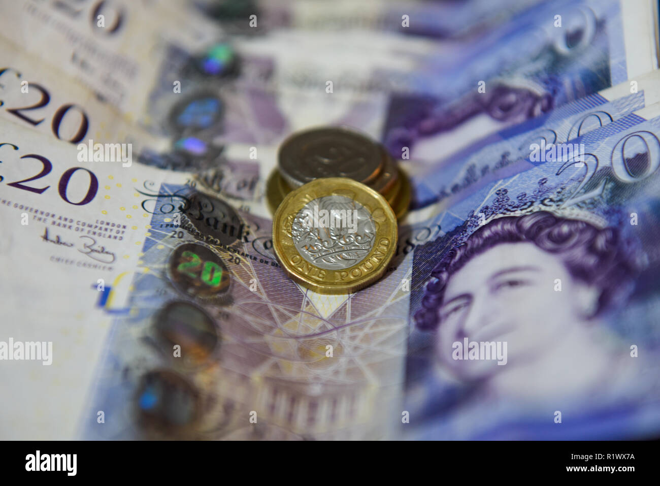 Twenty pounds bank notes and one pound coin are seen displayed Stock ...