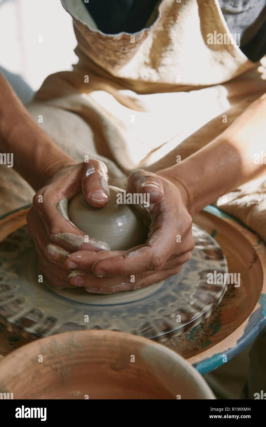 selective focus of professional potter working on pottery wheel at ...