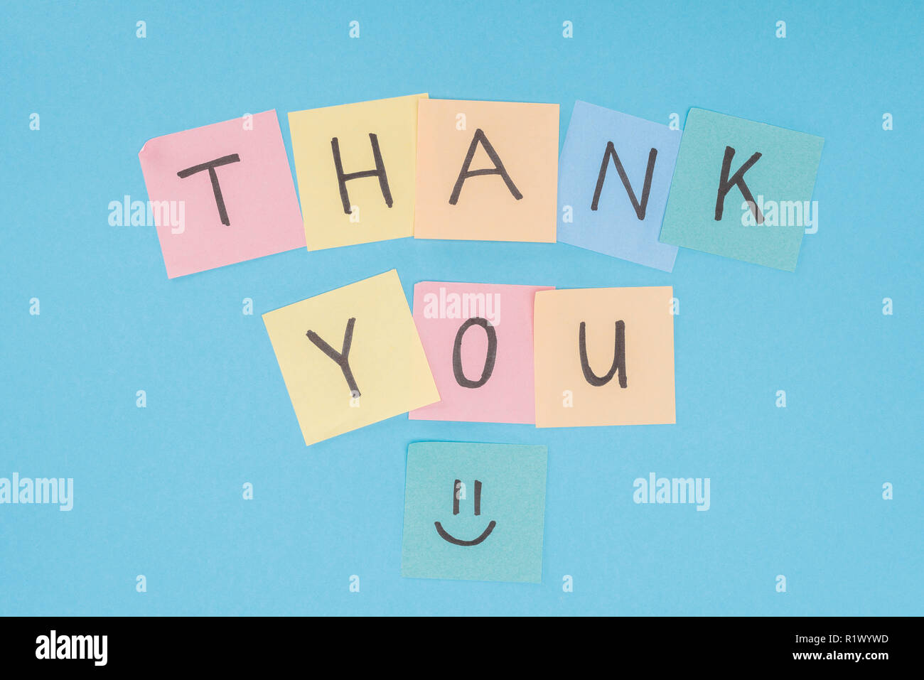 colorful sticky notes spelling thank you isolated on blue background ...