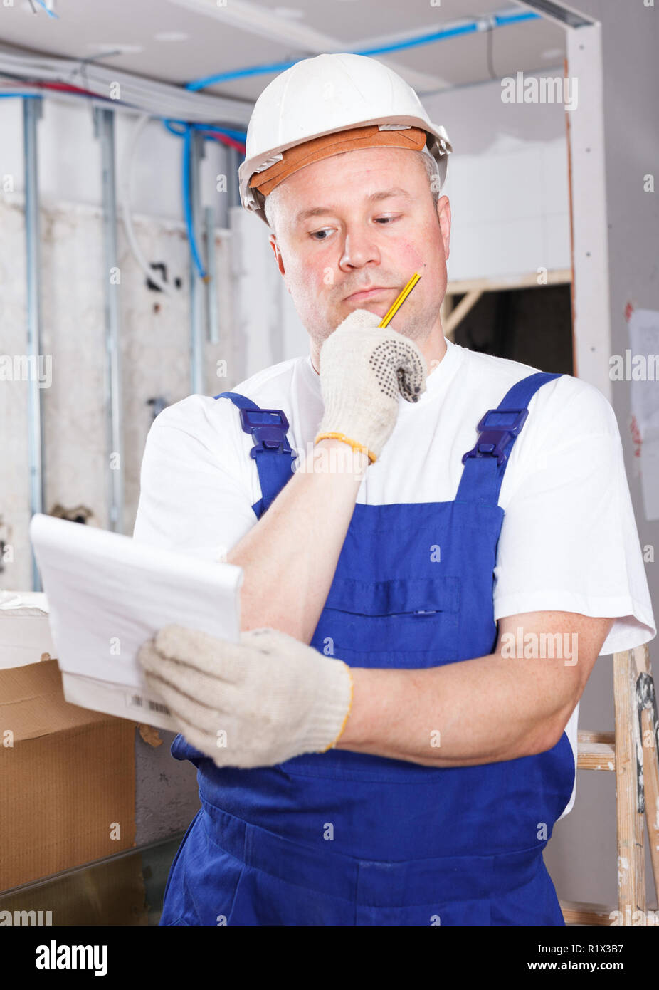 Professional male contractor looking at room and determining scope of ...