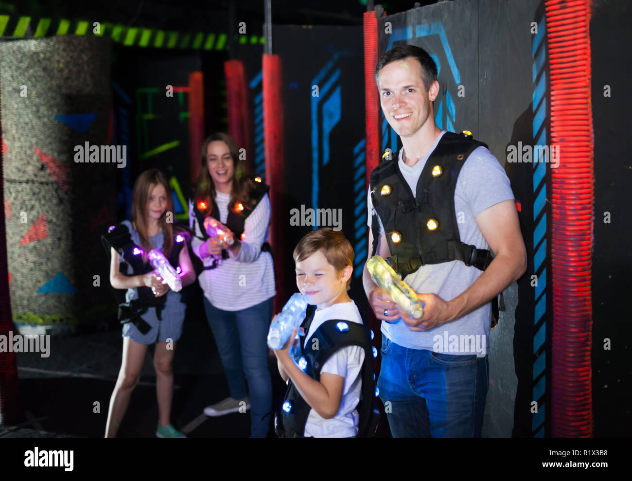 Portrait of young modern father and little son with laser pistols ...