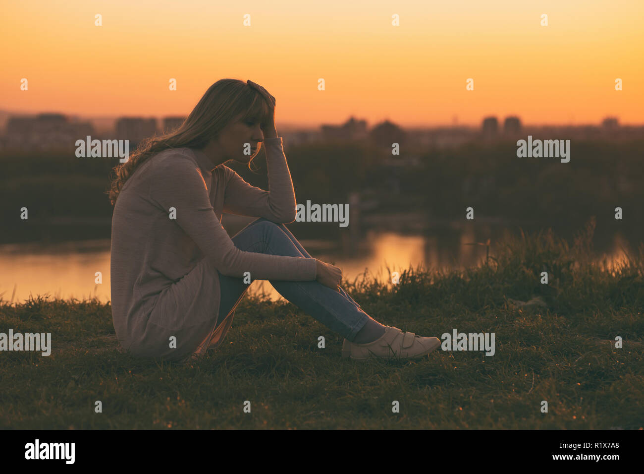 Sad woman sitting at the sunset and thinking Stock Photo - Alamy