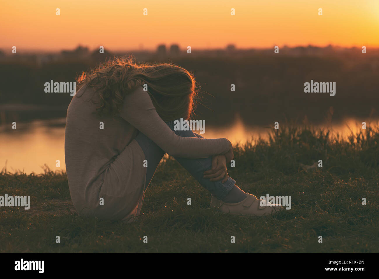 Sad woman sitting at the sunset Stock Photo - Alamy