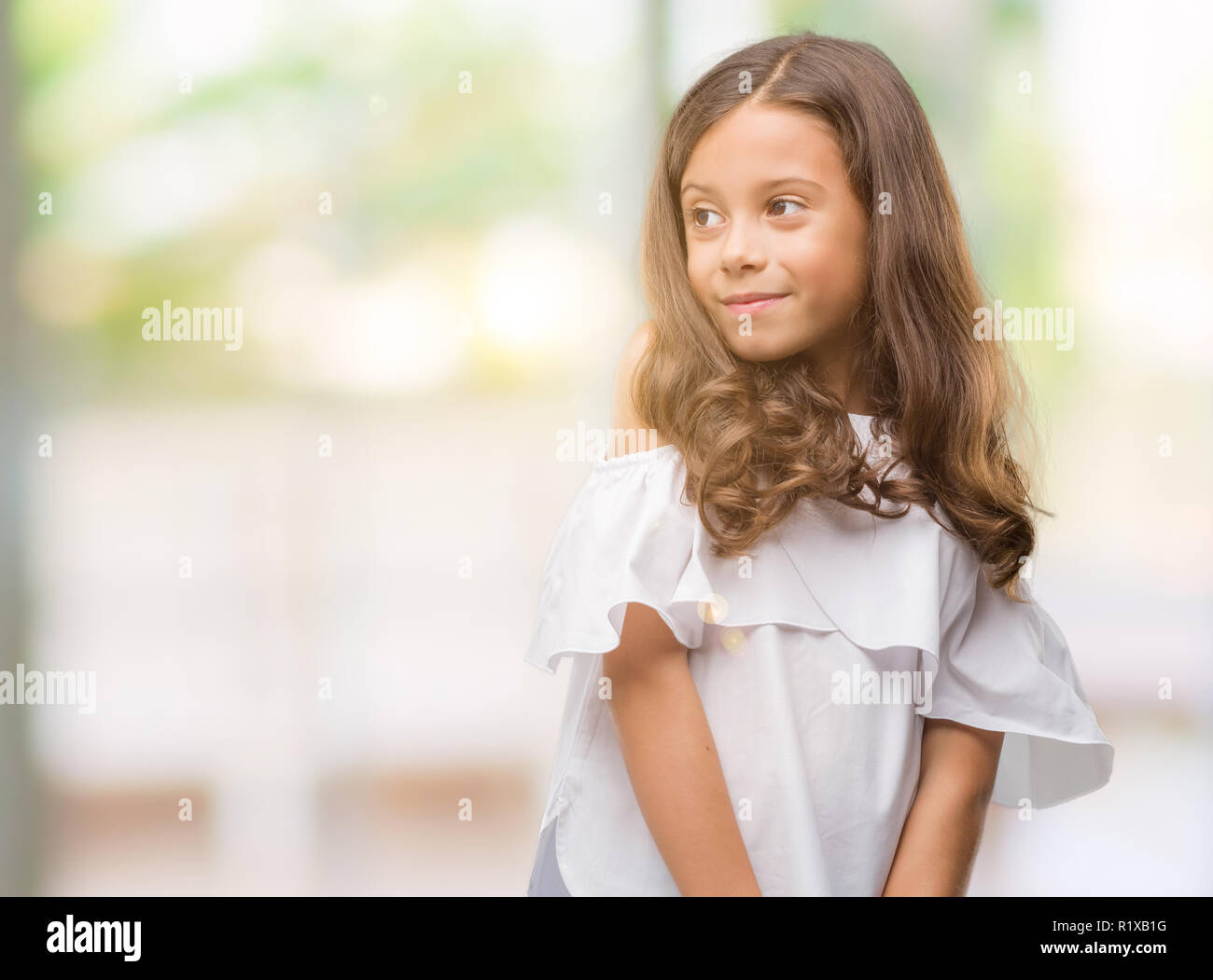 Brunette hispanic girl looking away to side with smile on face, natural ...