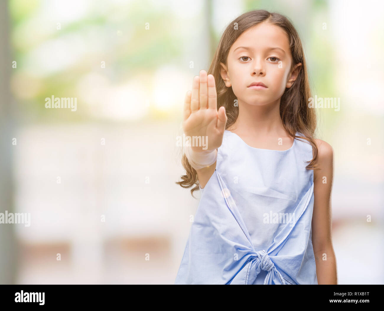 Brunette hispanic girl doing stop sing with palm of the hand. Warning ...