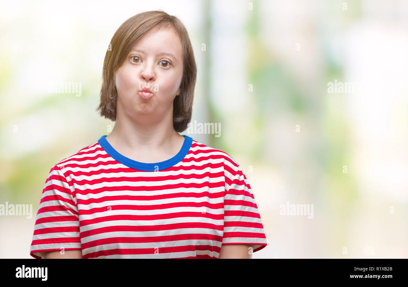 Young adult woman with down syndrome over isolated background puffing ...