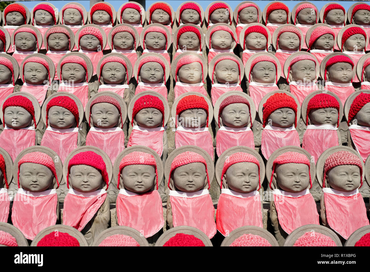 row of buddhist mizuko jizo statues with red bib, hat Stock Photo - Alamy